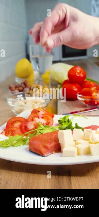 Close-up vertical video of a male hand sprinkles fish and cheese with ...