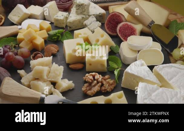 Variety of sliced cheeses with fruits, mint, nuts and cheese cutting ...