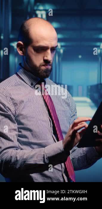 Vertical video: Data center IT engineer standing in server room with ... Vertical video: Data center IT engineer standing in server room with ...