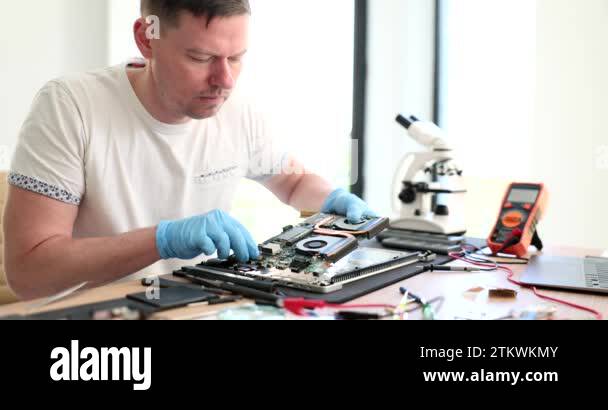 Engineer repairs laptop and disassembled computer parts. Electronic ...