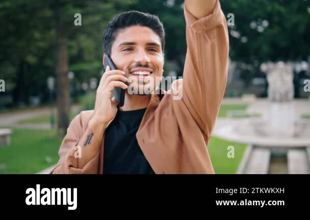 Calling man waving hand at park close up. Happy guy talking mobile ...