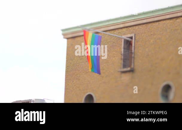 Rainbow flag hanging vertically on a flag pole off a brick building Stock Video Footage - Alamy