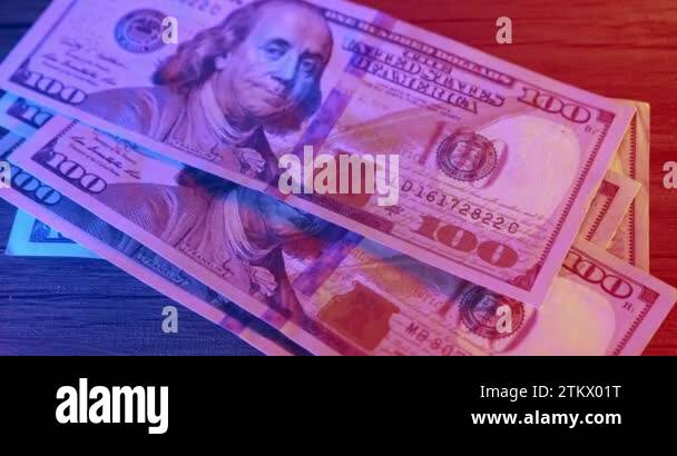Cash dollars are placed on table at night at neon lighting, counting ...