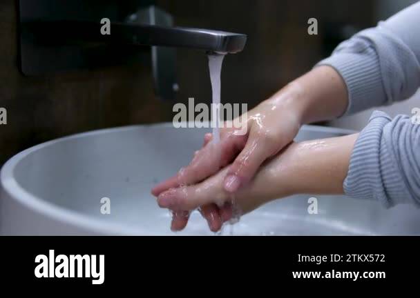 Close up of biracial woman washing hands in bathroom, slow motion. Self ...