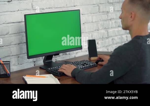 Man Looks at Computer Green Screen and Writes Something in Notebook ...