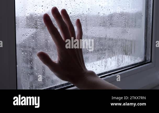 Woman Touches a Wet Misted Window with Hand. Fingers slide on wet glass ...