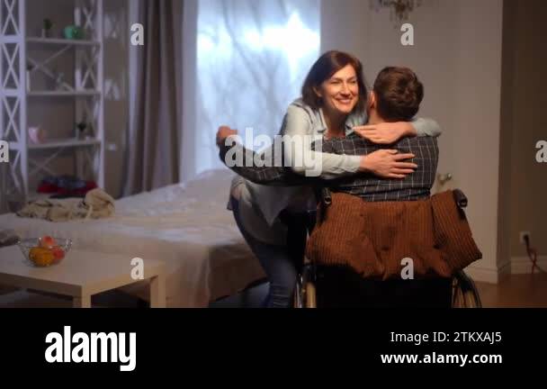 Loving smiling wife hugging husband in wheelchair caressing back of ...