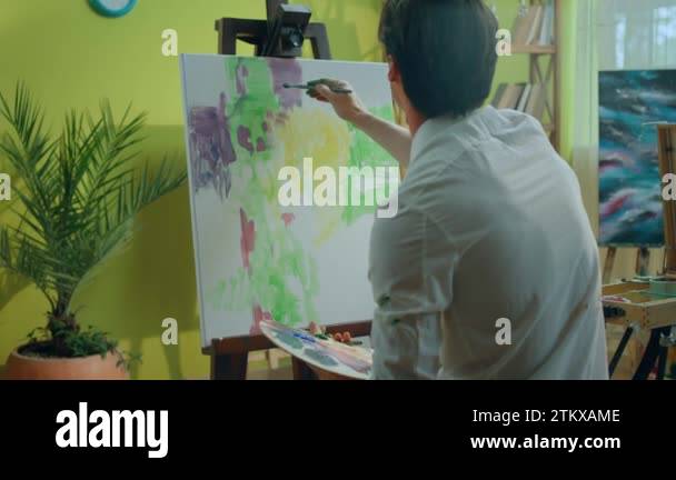 Charismatic artist man in the art studio painting on canvas new picture ...