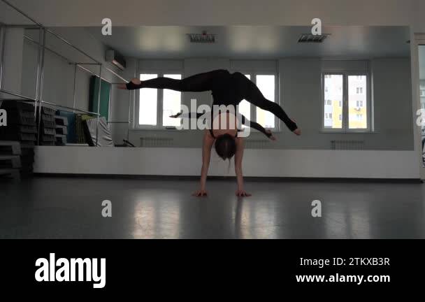 girl gymnast pulls leg to head arching in the back, stretching in ...