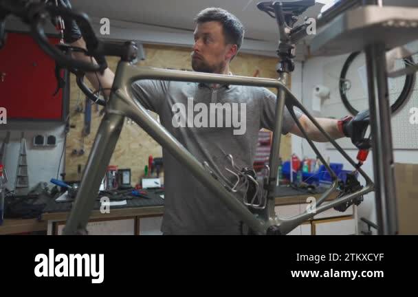 Bicycle mechanic holding syringe with brake fluid during brake bleeding process. Cycle repairman ...