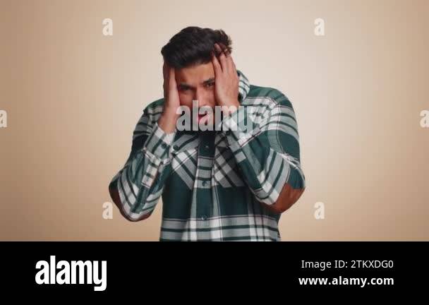 Young indian man scared fearful, covering ears with hands, closing eyes ...