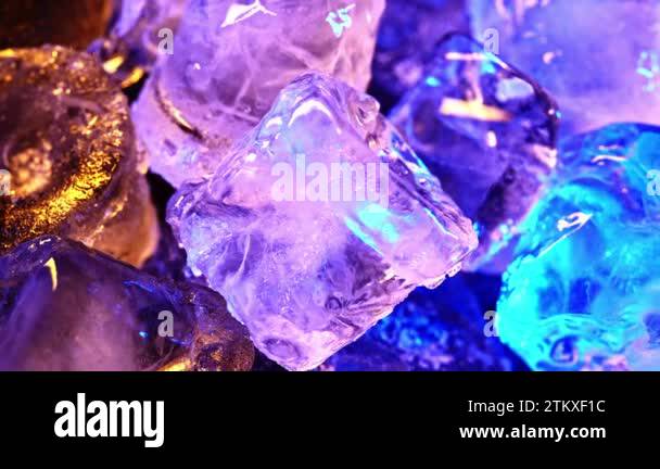 Multi-colored paint spreads over the surface of the ice cubes and flows ...