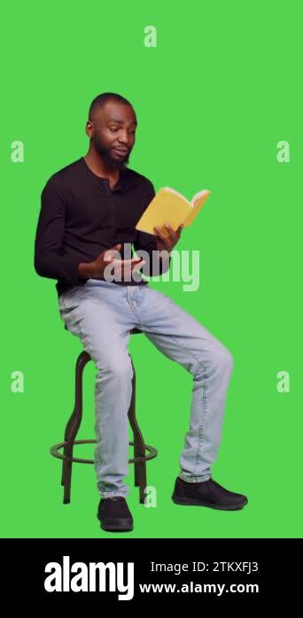 Vertical video: Side view of male model reading novel story on book in ...