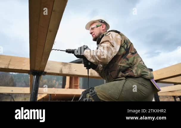 Man building wooden frame house. Worker drilling hole by electric drill ...