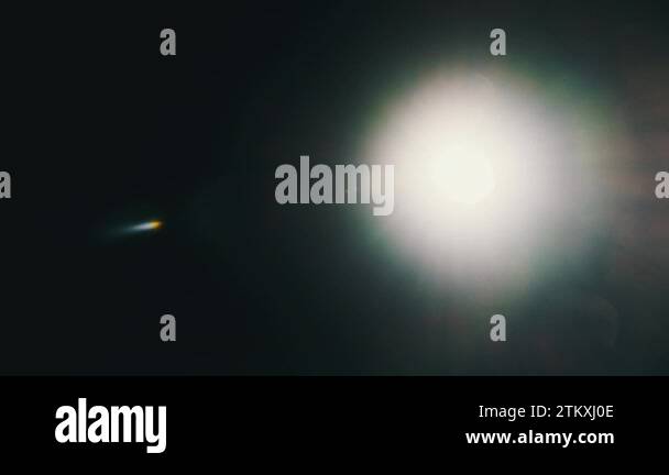 The light of a bright flashlight directed at the camera moves from side ...