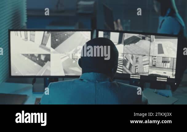 Back view of Black male security guard watching multiple CCTV outdoor ...