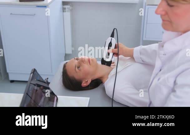 a doctor in a modern diagnostic clinic examines the thyroid gland of a ...