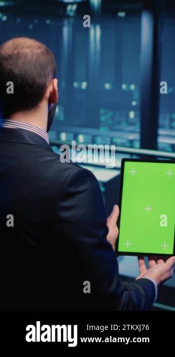 Vertical video: Data center technician holding tablet with green screen ... Vertical video: Data center technician holding tablet with green screen ...