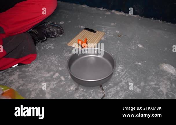 A guy cooks food on gas inside an ice cave. The climber lights the ...