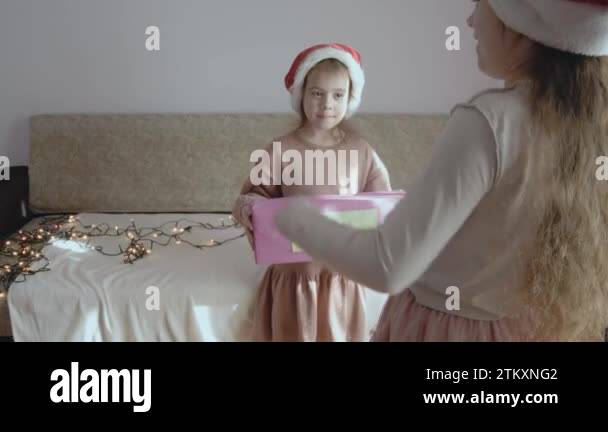 Happy little girl holding a mystery gift box. Another girl shows ...