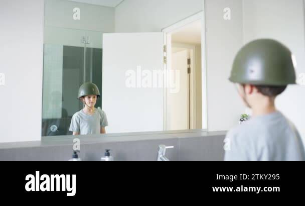 Pretend soldier, child with helmet in home and salute in mirror in ...