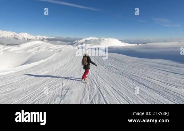 Lady snowboarding on a scenic ski slope with stunning view of snowy ...