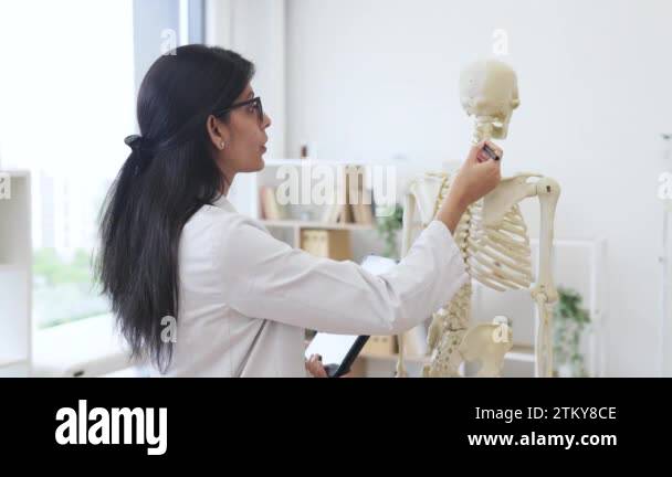 Side view of hindu medical worker with tablet pointing at spine while ...