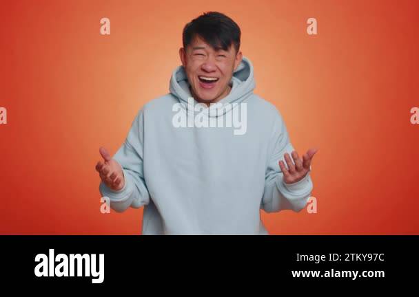 Amused asian man pointing finger to camera, laughing out loud, taunting ...