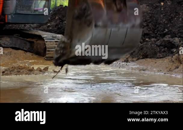 excavator bucket to draw water in the flooded ditch at a construction ...
