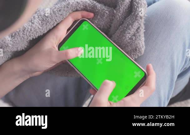 Teenager girl playing game on phone with green screen. Phone with greenscreen and chroma key for ...