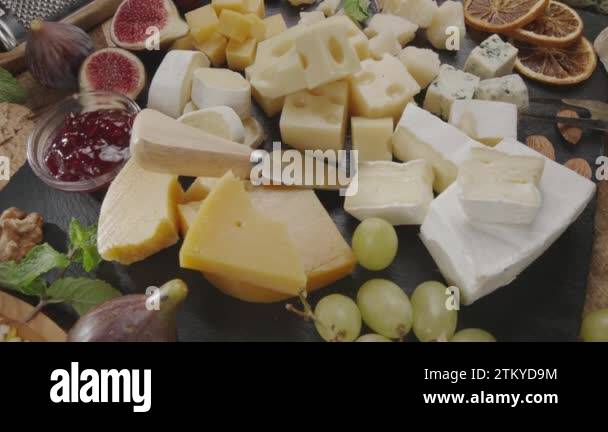Variety of sliced cheeses with fruits, mint, nuts and cheese cutting ...