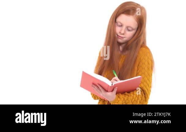 Cute school girl doing her homework. She writes notes to workbook ...