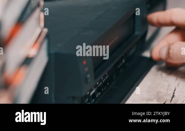Eject VHS tape cassette from VCR player. Male hand pushes a button and ...