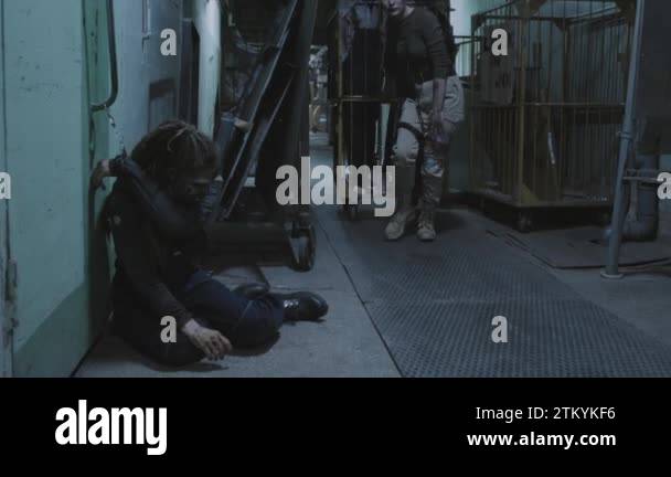 Injured female soldier with shaved head transporting zombies in cage on ...
