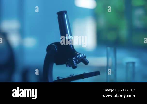 The camera moves across the microscope in a dark laboratory with soft blue light. Laboratory ...