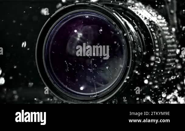 Drops of water fall on a camera with a lens. Filmed on a high-speed ...
