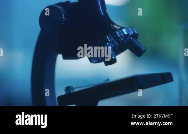 The camera moves across the microscope in a dark laboratory with soft ...