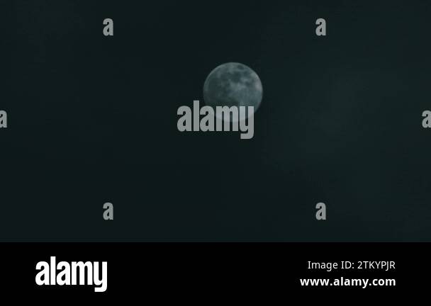 The full moon in the night sky glows through dark clouds. Mystical ...