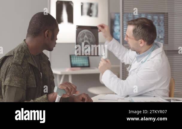 Waist up slowmo of Caucasian male doctor showing Black army officer in ...