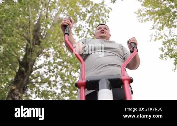 Young fat man running on exercise machine in park, panting, sustainable ...