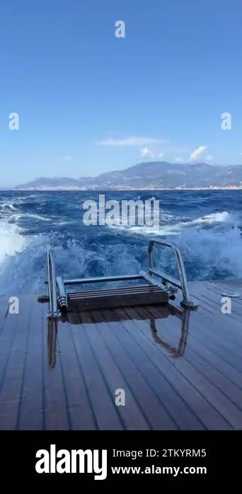 slipstream behind and splashing water on the wooden dock ladder of the ...