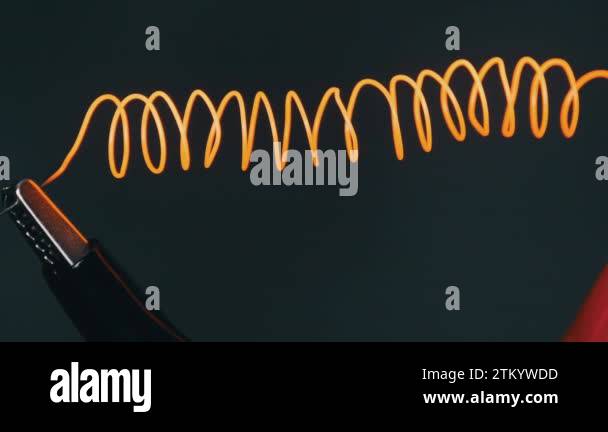 Nichrome filament connected to power wires is heated to red under the ...