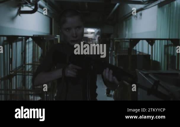 Waist-up of female soldier with shaved head walking in basement of ...