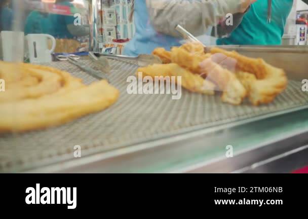 Fresh churro productions. Street food vendor prepares churros squeezing ...