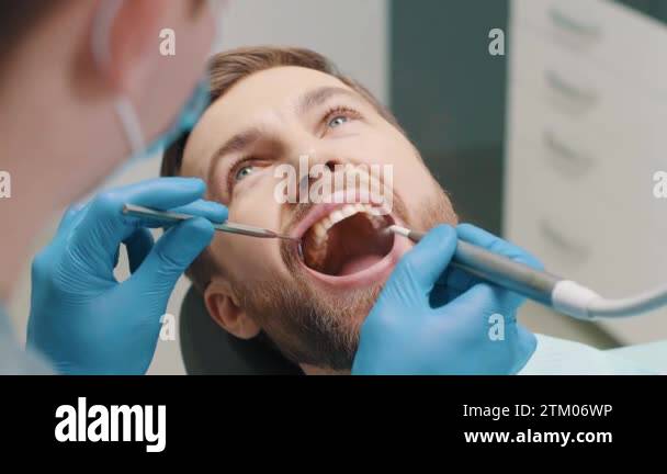 Treatment of teeth in a male patient, a dentist performs a hygienic ...