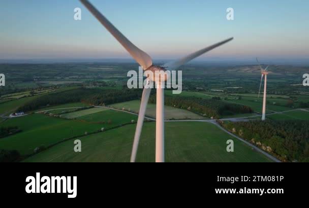 Aerial. White turbines standing at sunset. Aerial photo of a farm with ...