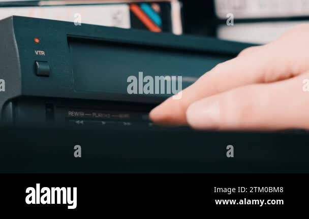 Eject VHS tape cassette from VCR player. Male hand pushes a button and ...
