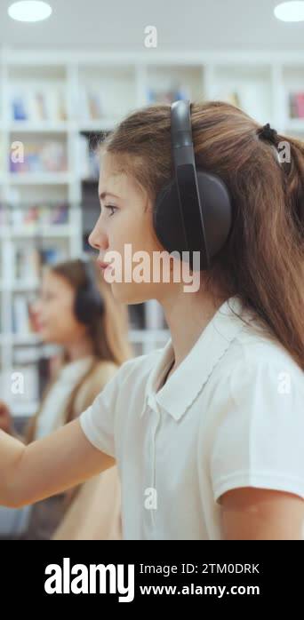 Vertical Screen: Pupil wearing headphones sitting in class and using ...