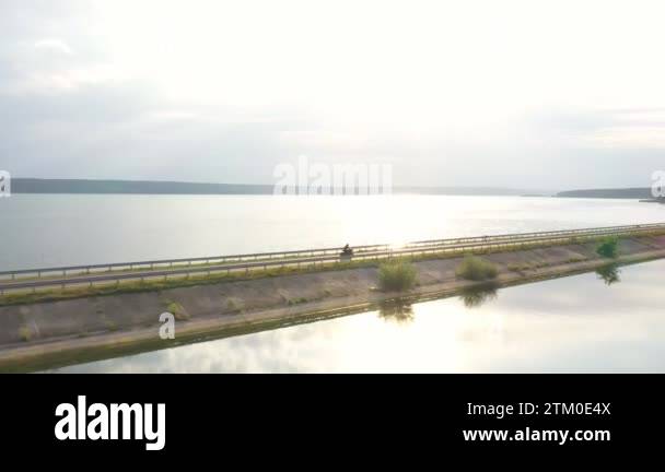 Aerial view to biker riding on motorbike at dam route with sunshine at ...