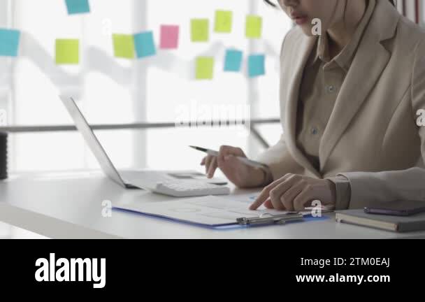 Beautiful young Asian accountant using calculator to calculate savings ...